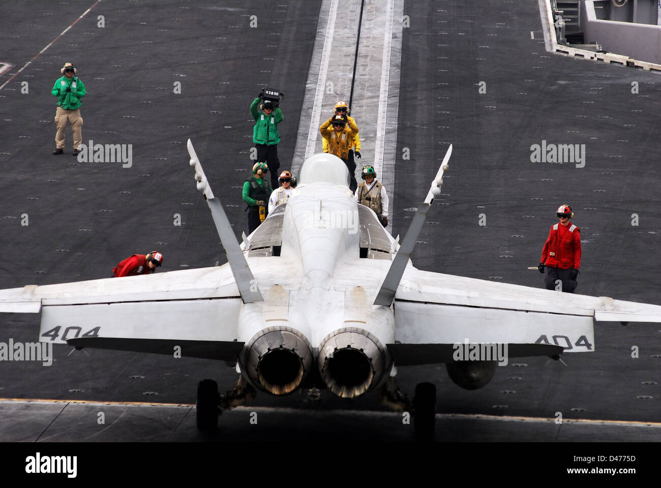 An F/A-18E Super Hornet is directed onto a catapult aboard USS Ronald ...