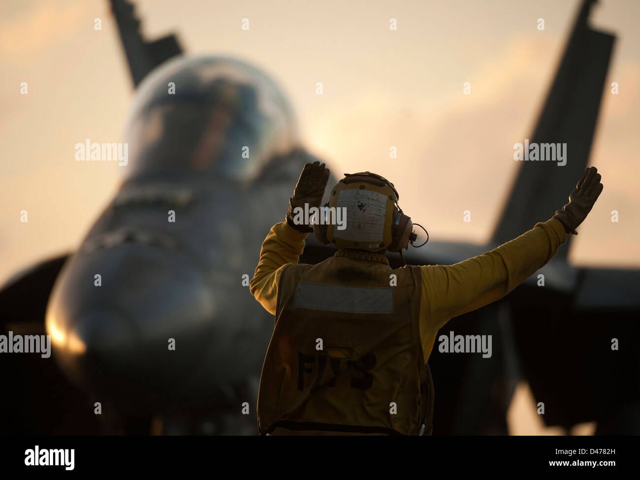 An aircraft director aboard a U.S. Navy aircraft carrier guides a jet ...