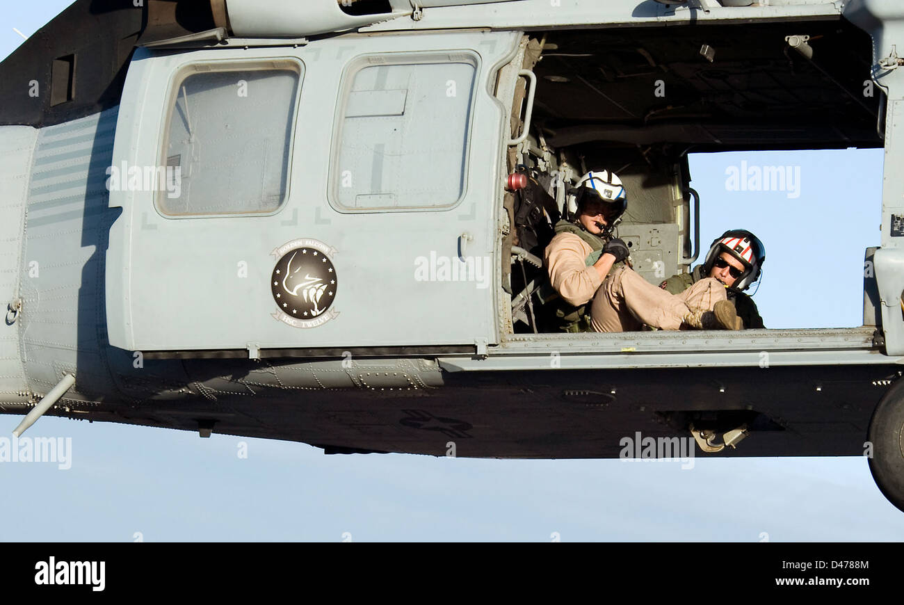 A U.S. Navy helicopter hovers above the flight deck of a ship during a ...