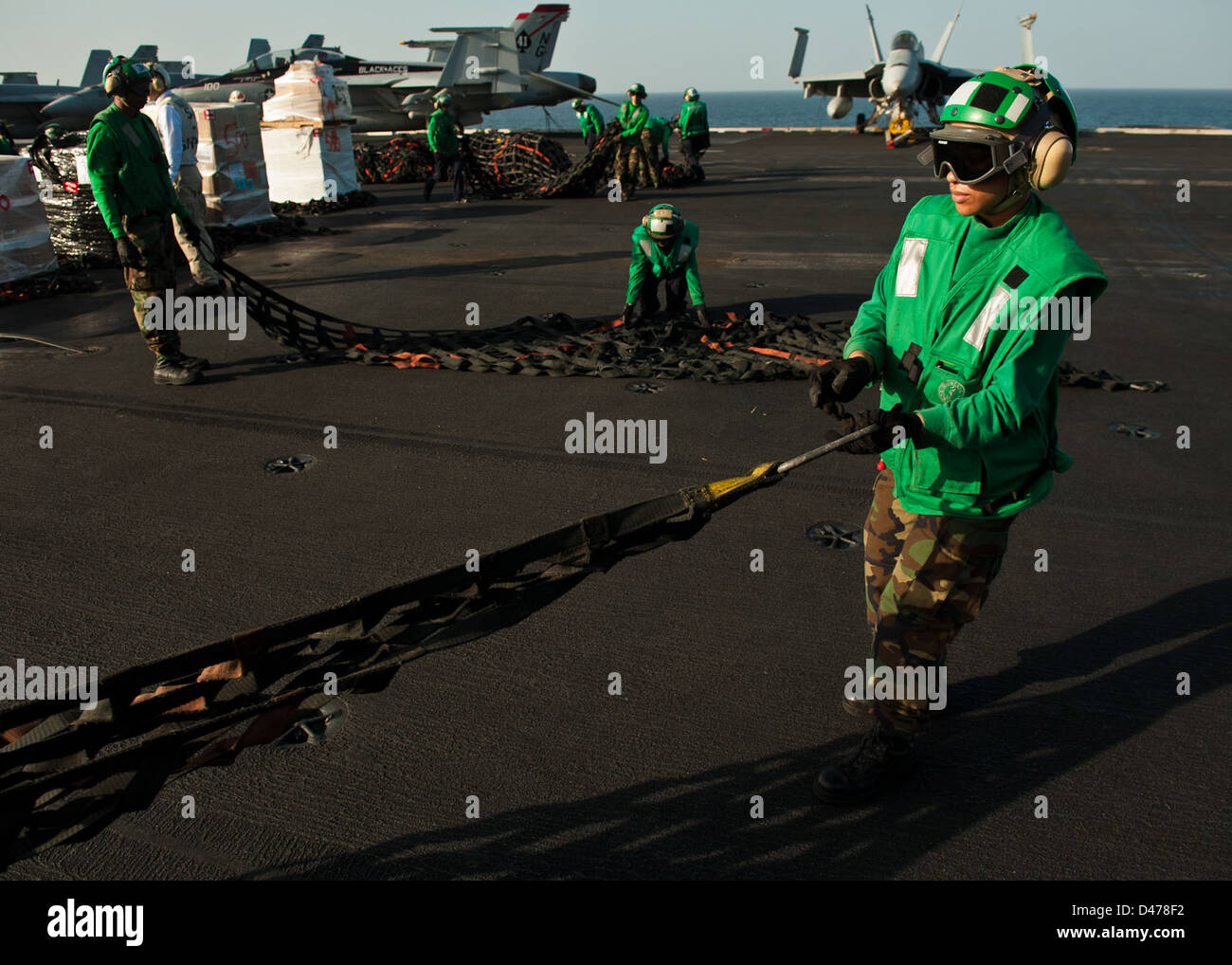 A Sailor aboard a U.S. Navy ship bundles a cargo net during a vertical ...