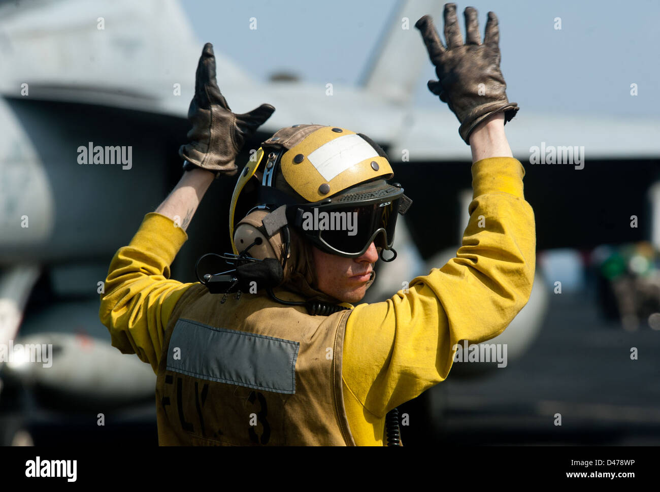 A U.S. Navy sailor directs the launch of a fixed-wing aircraft aboard ...