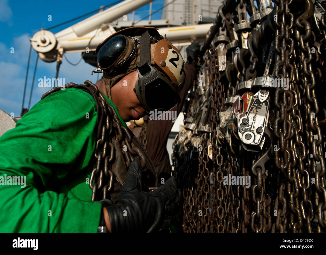 A U.S. Navy sailor returns chains after flight operations aboard a ship ...