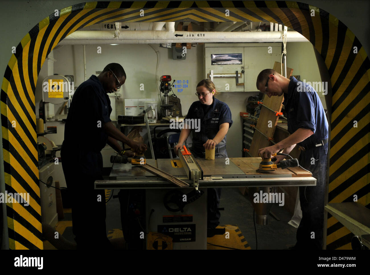 Sailors work in the carpentry shop aboard a U.S. Navy ship in the ...