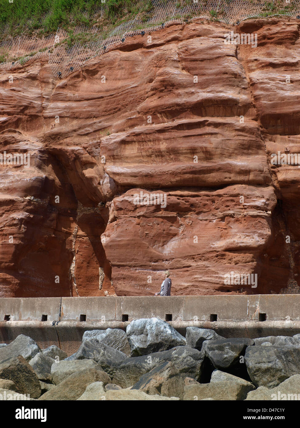 Red sandstone rock at Sidmouth with walkway underneath Stock Photo - Alamy
