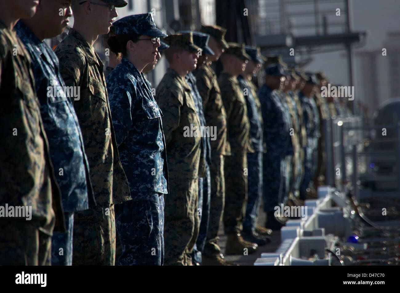 Sailors and Marines aboard a U.S. Navy ship man the rails in ...