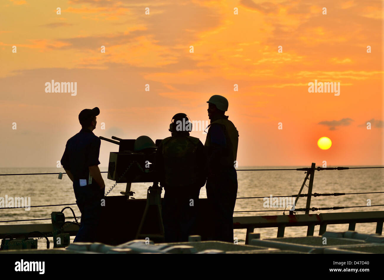 Sailors aboard a naval vessel operate a crew-served weapon during an ...
