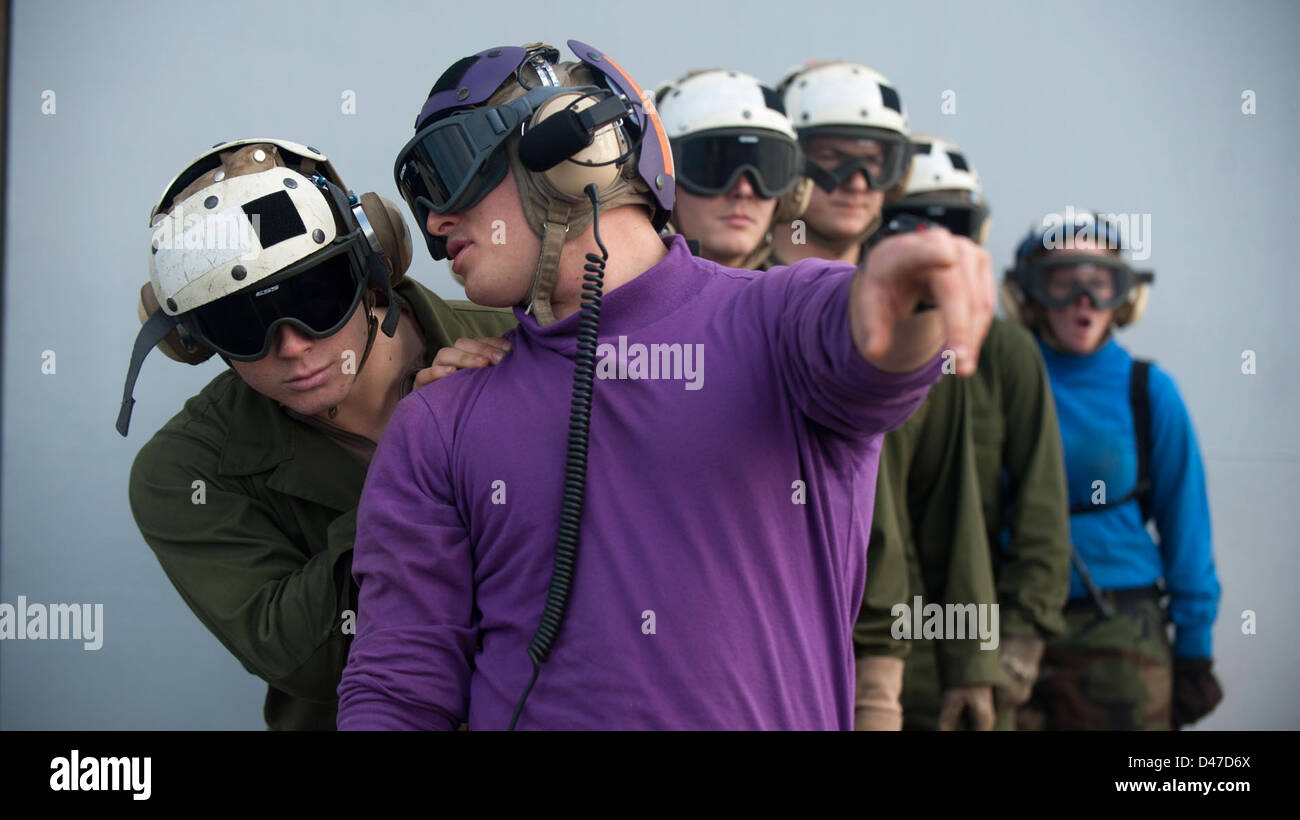 A U.S. Navy Sailor provides guidance to a Marine on the flight deck of ...