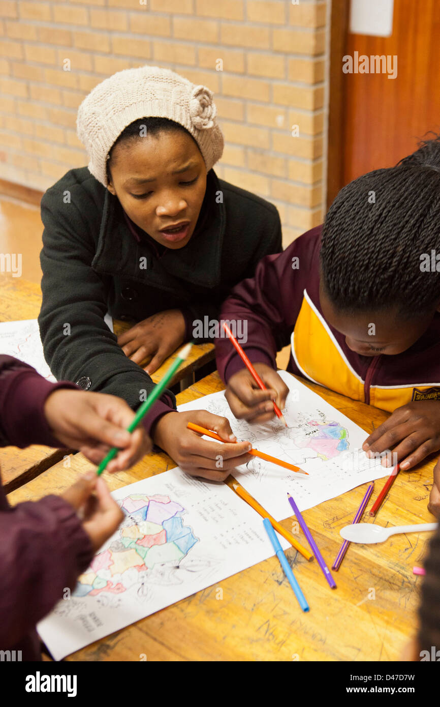 African primary school children coloring in maps of Africa on a desk in ...
