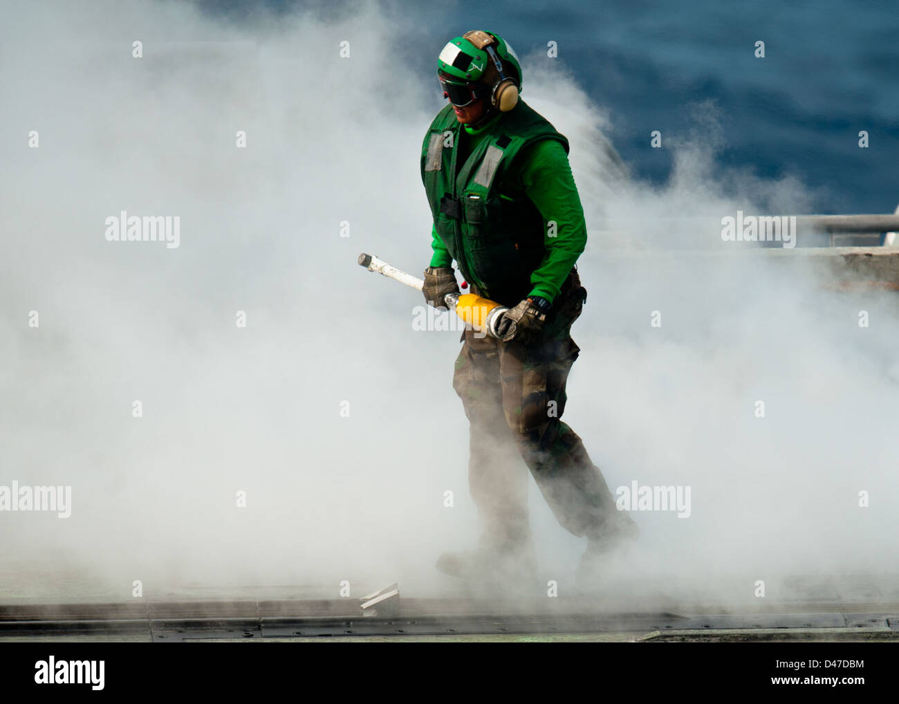 A Sailor collects a hold-back bar during flight operations Stock Photo ...