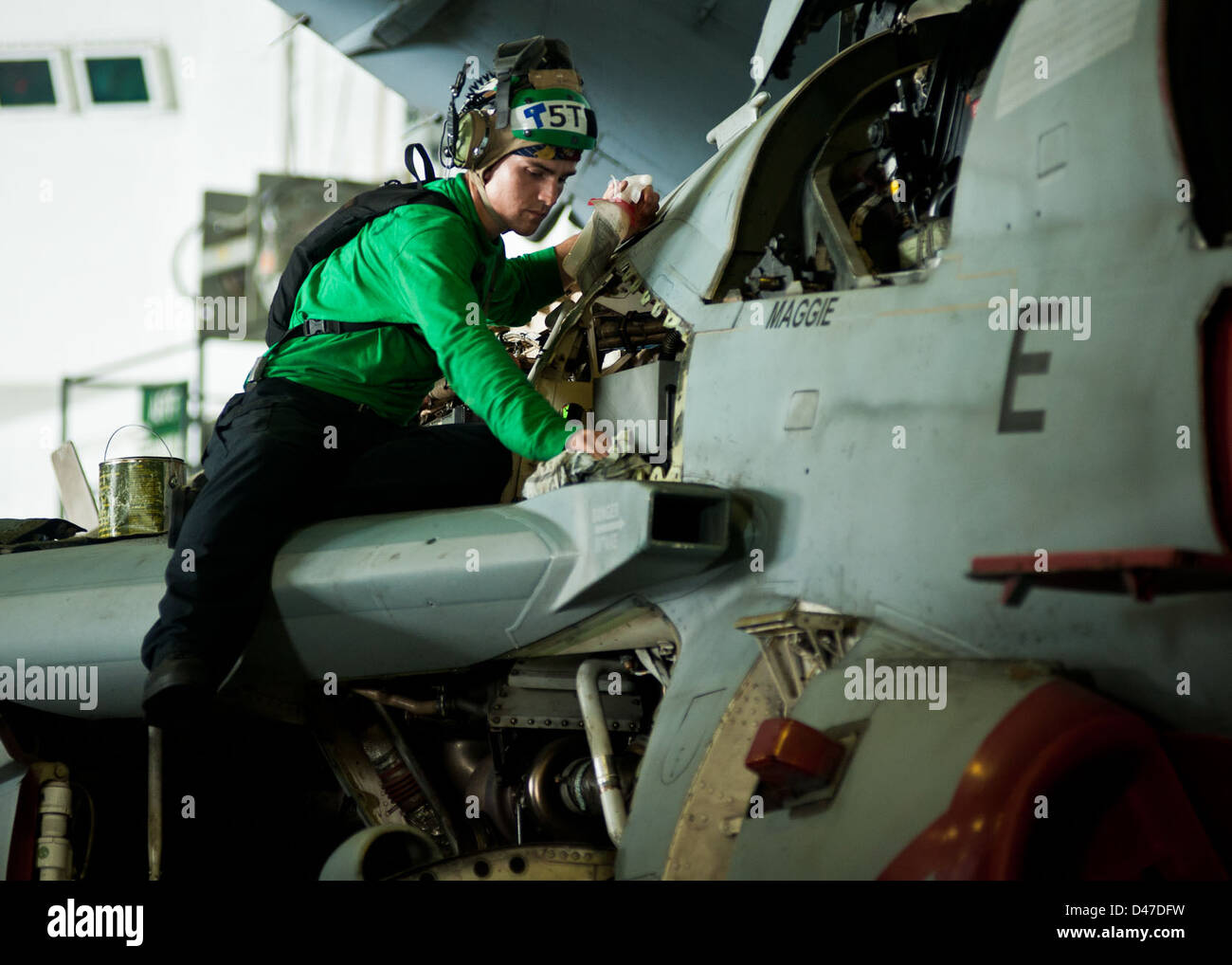 A U.S. Navy sailor performs routine maintenance, cleaning an aircraft ...