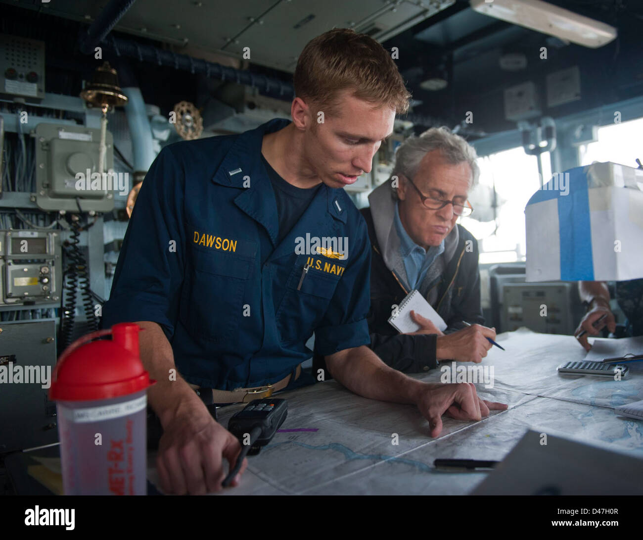A U.S. Navy Sailor explains navigation chart details, assisting in ...