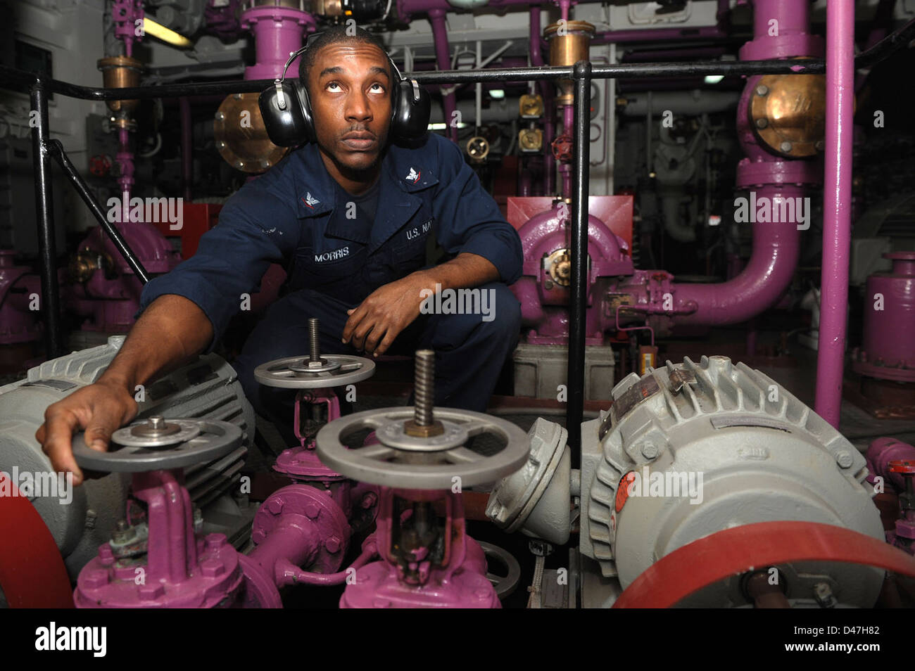 A Sailor adjusts pressure on motor stripping pumps aboard a naval ship ...
