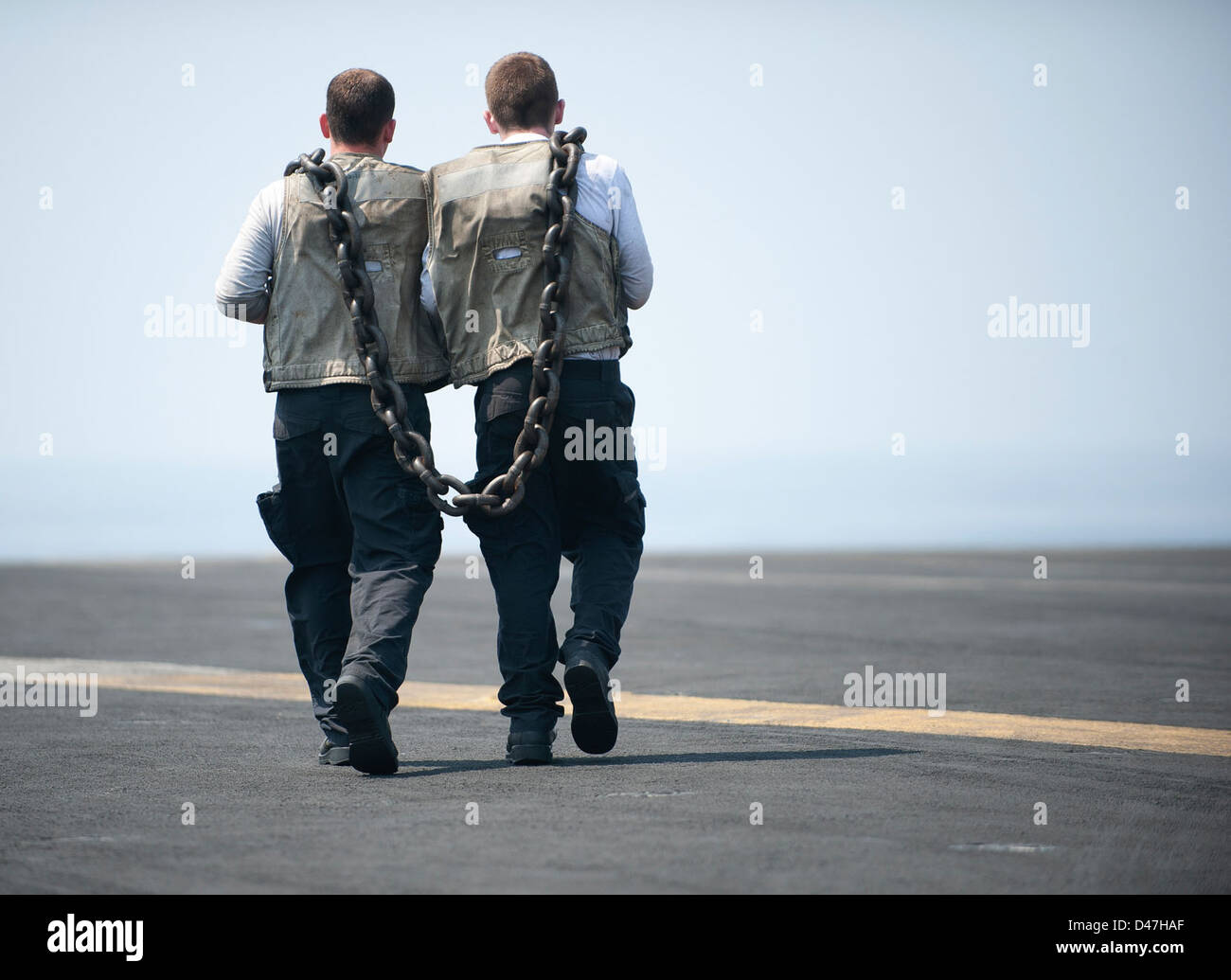 Sailors handle heavy chains on the flight deck to secure aircraft for ...