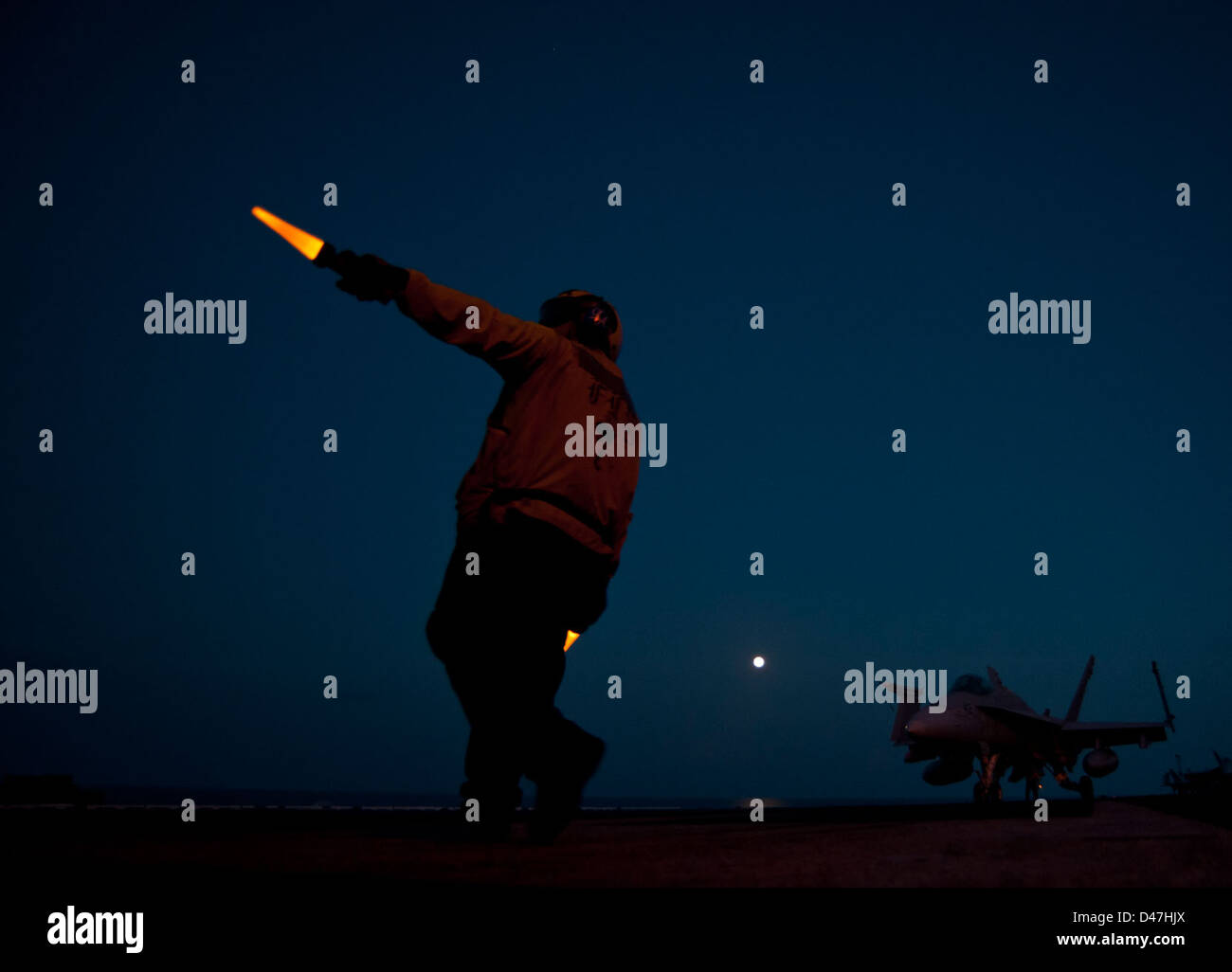 An aircraft director on the flight deck signals to the pilots of an F/A ...