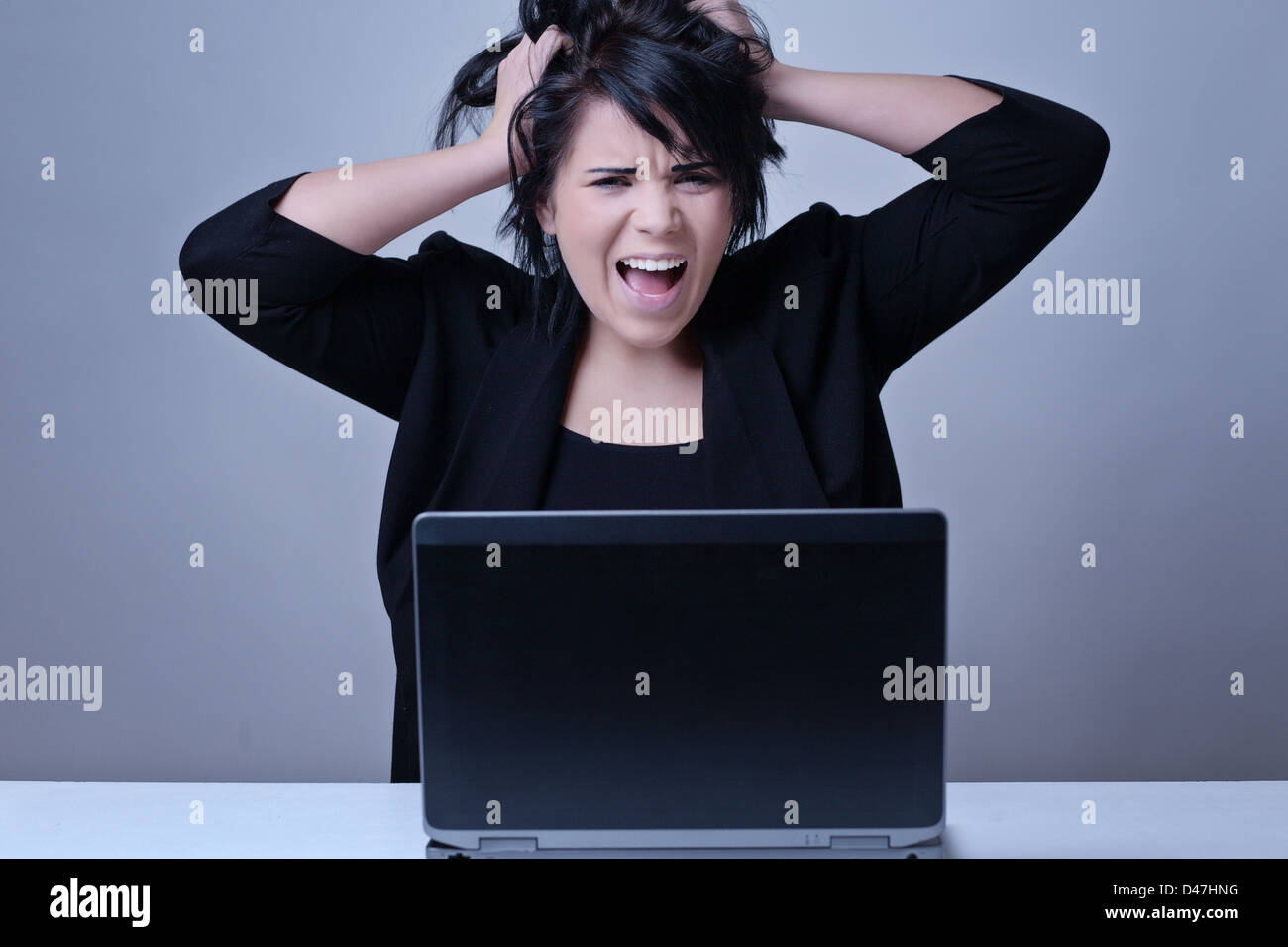 woman at her desk working on a laptop computer pulling out her hair ...