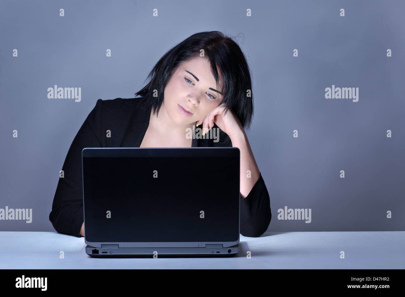 disinterested woman working at her desk over a laptop Stock Photo - Alamy