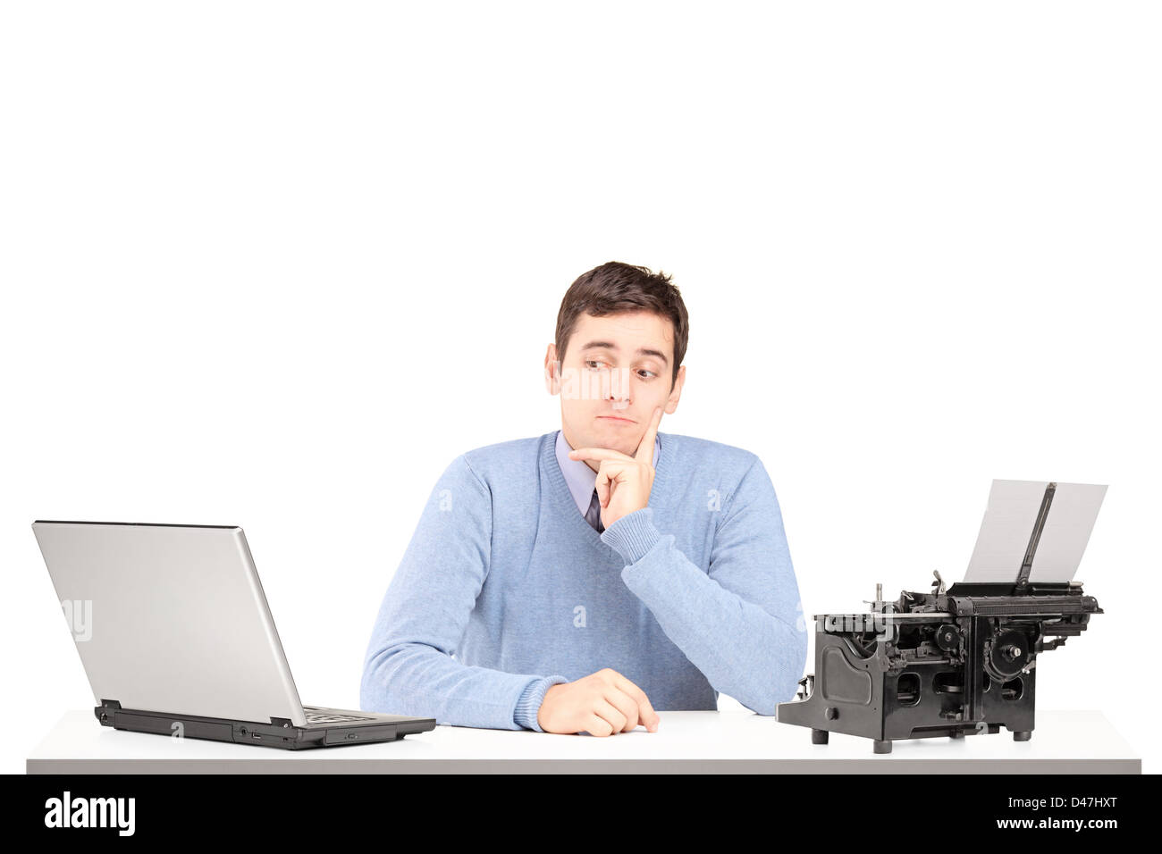 Confused man sitting on a desk with a laptop and a typing machine ...