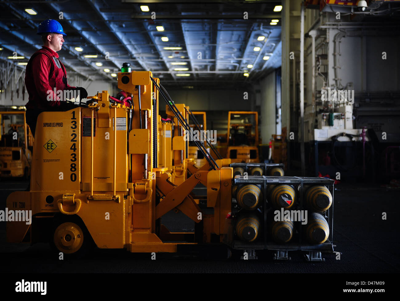 A U.S. Navy sailor operates a forklift to move ordnance in the hangar ...
