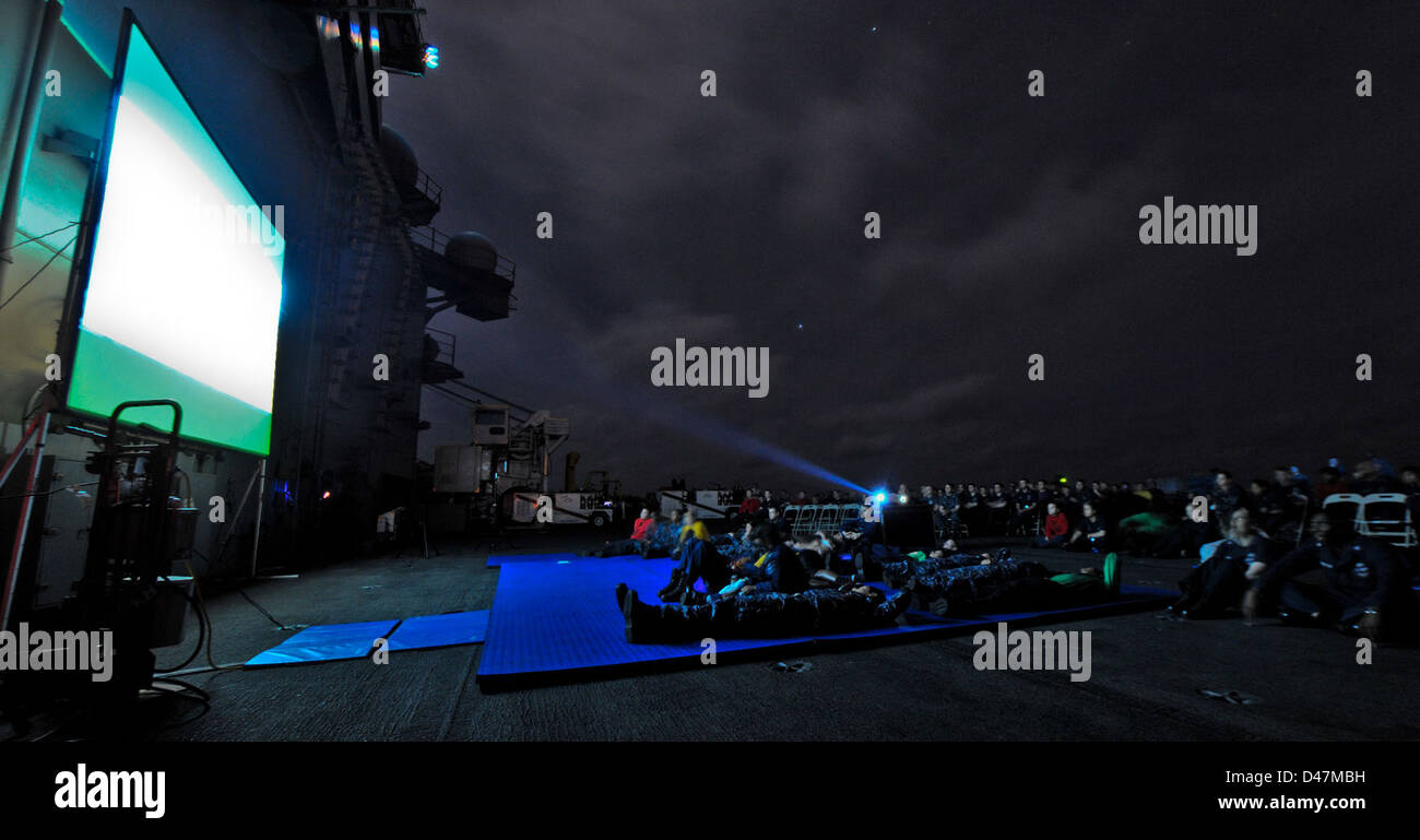 Sailors aboard USS George H.W. Bush watch a movie on the flight deck ...