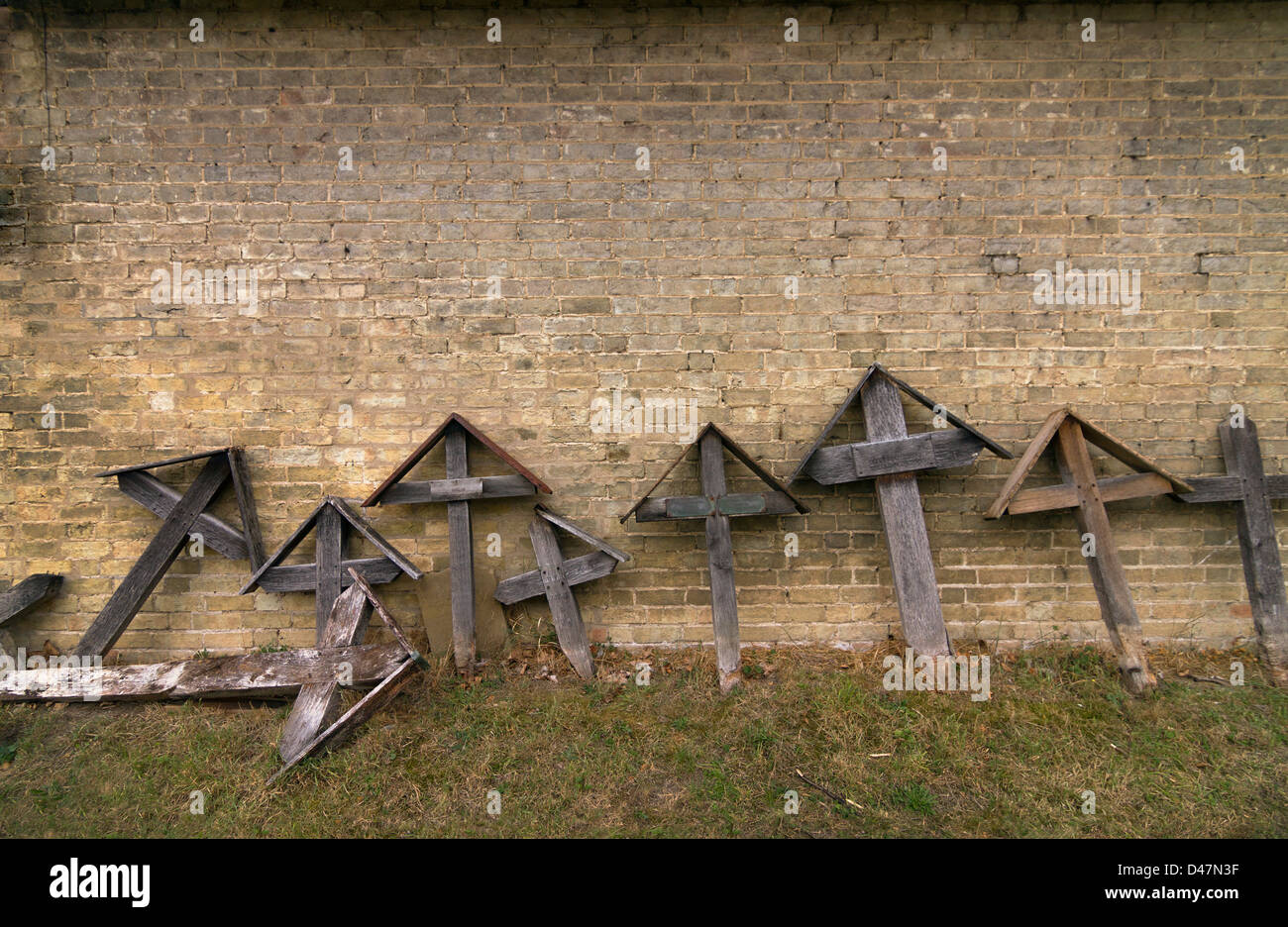 Old wooded crosses leaning up against a brick wall Stock Photo - Alamy