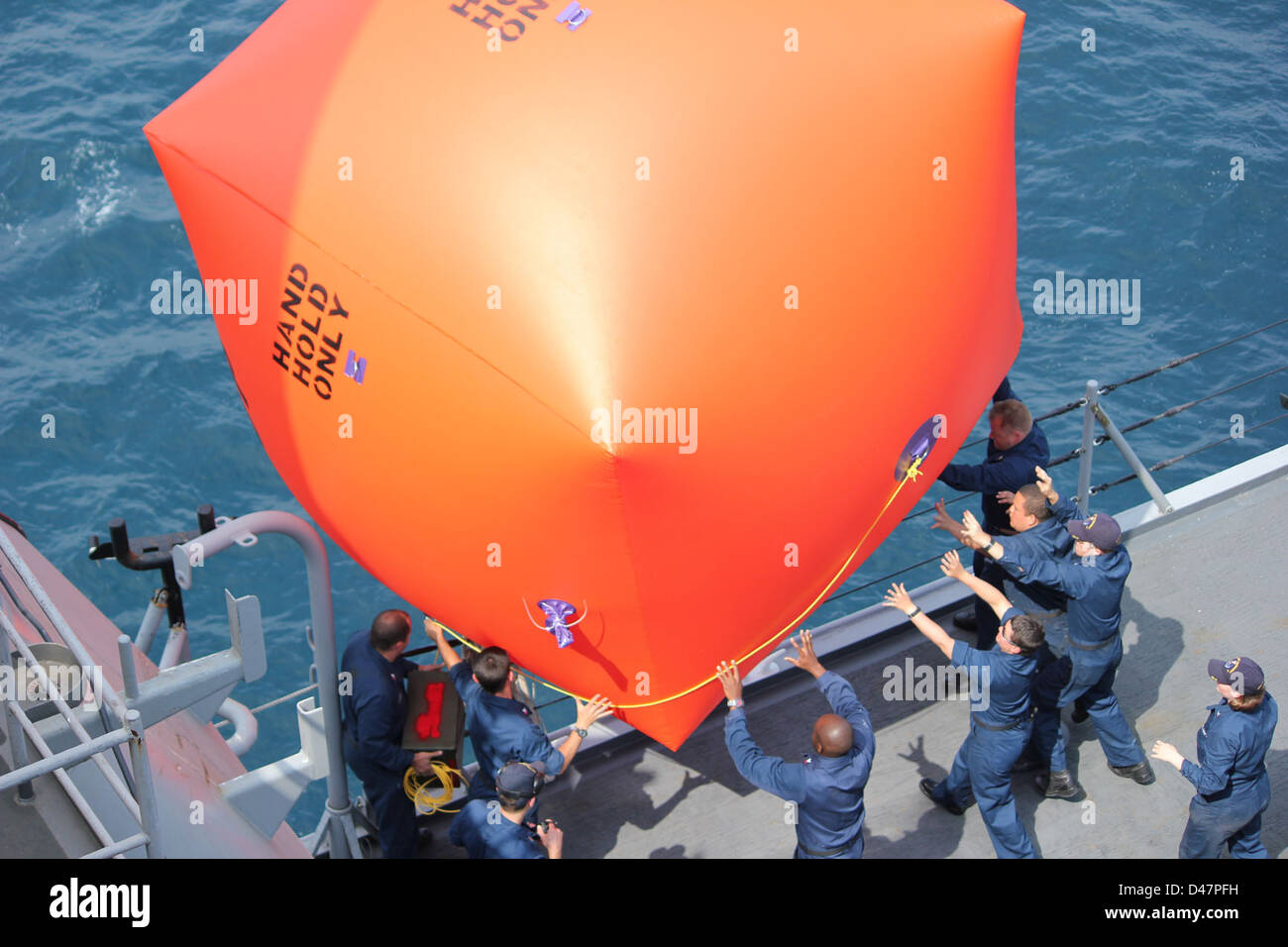 Sailors participate in a live-fire exercise by throwing a floating ...
