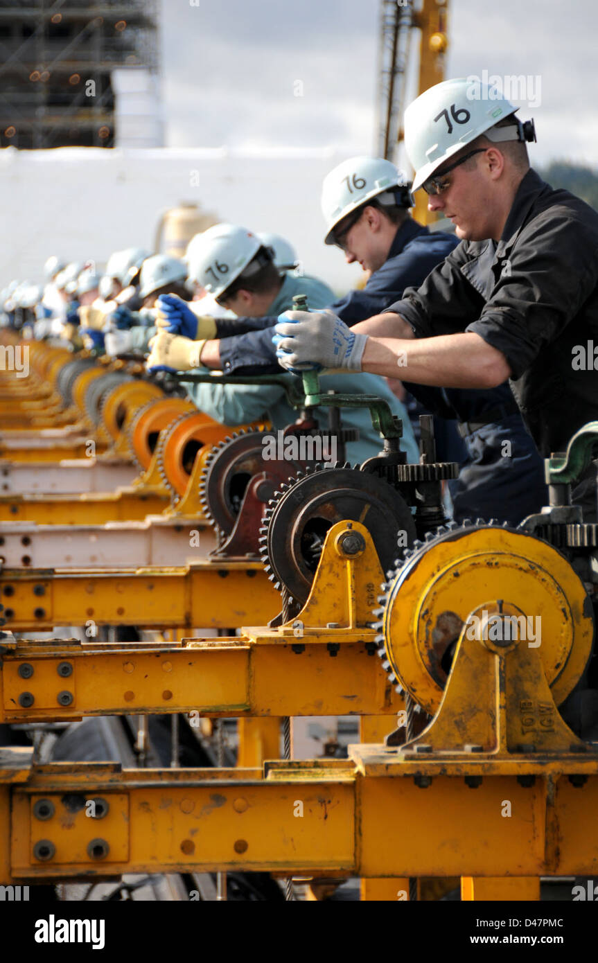 Sailors turn hand cranks to raise a steam-powered catapult chamber ...