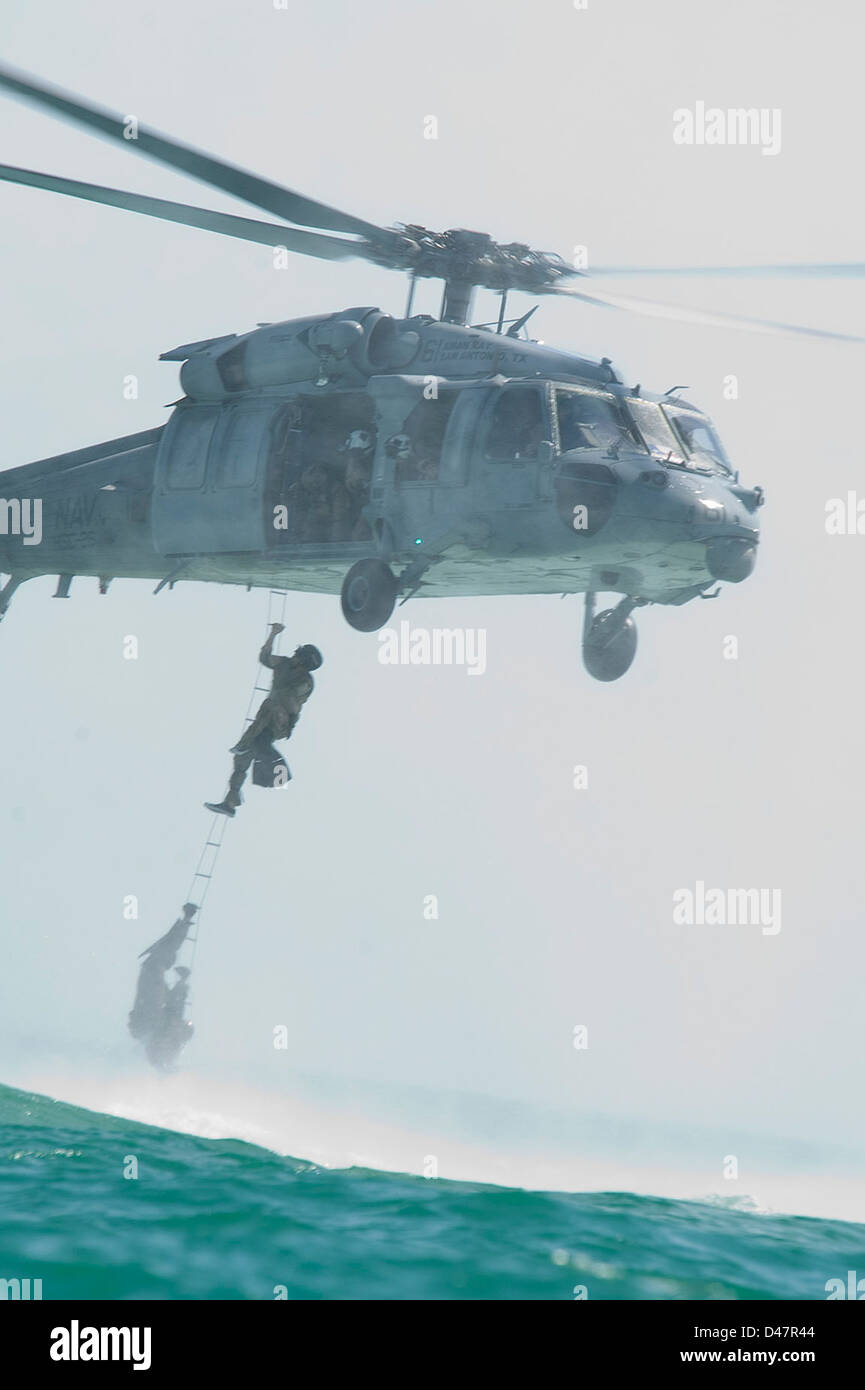 A Sailor climbs a ladder to board a helicopter during training in the ...