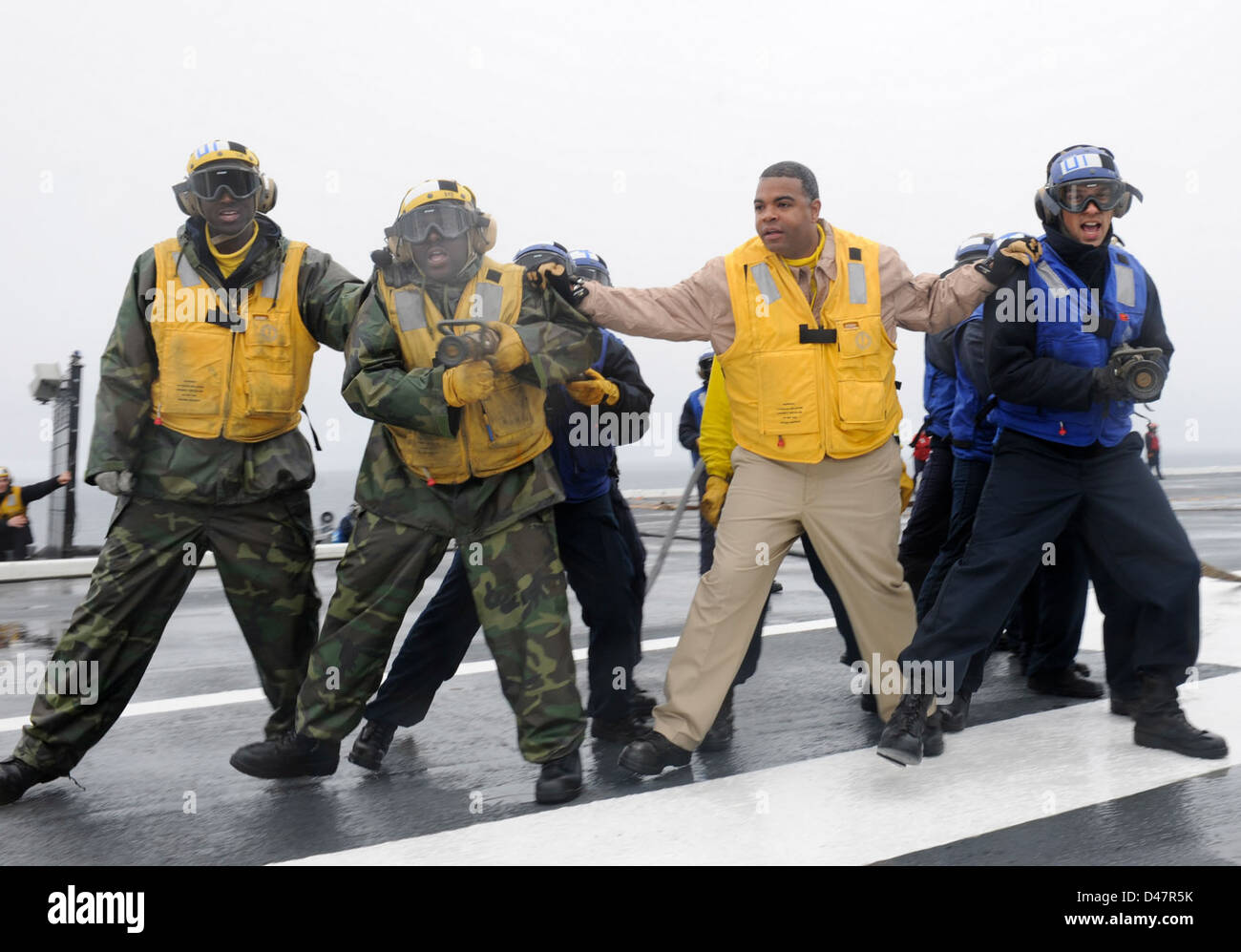 Sailors aboard a U.S. Navy ship in the Pacific Ocean work together as a ...