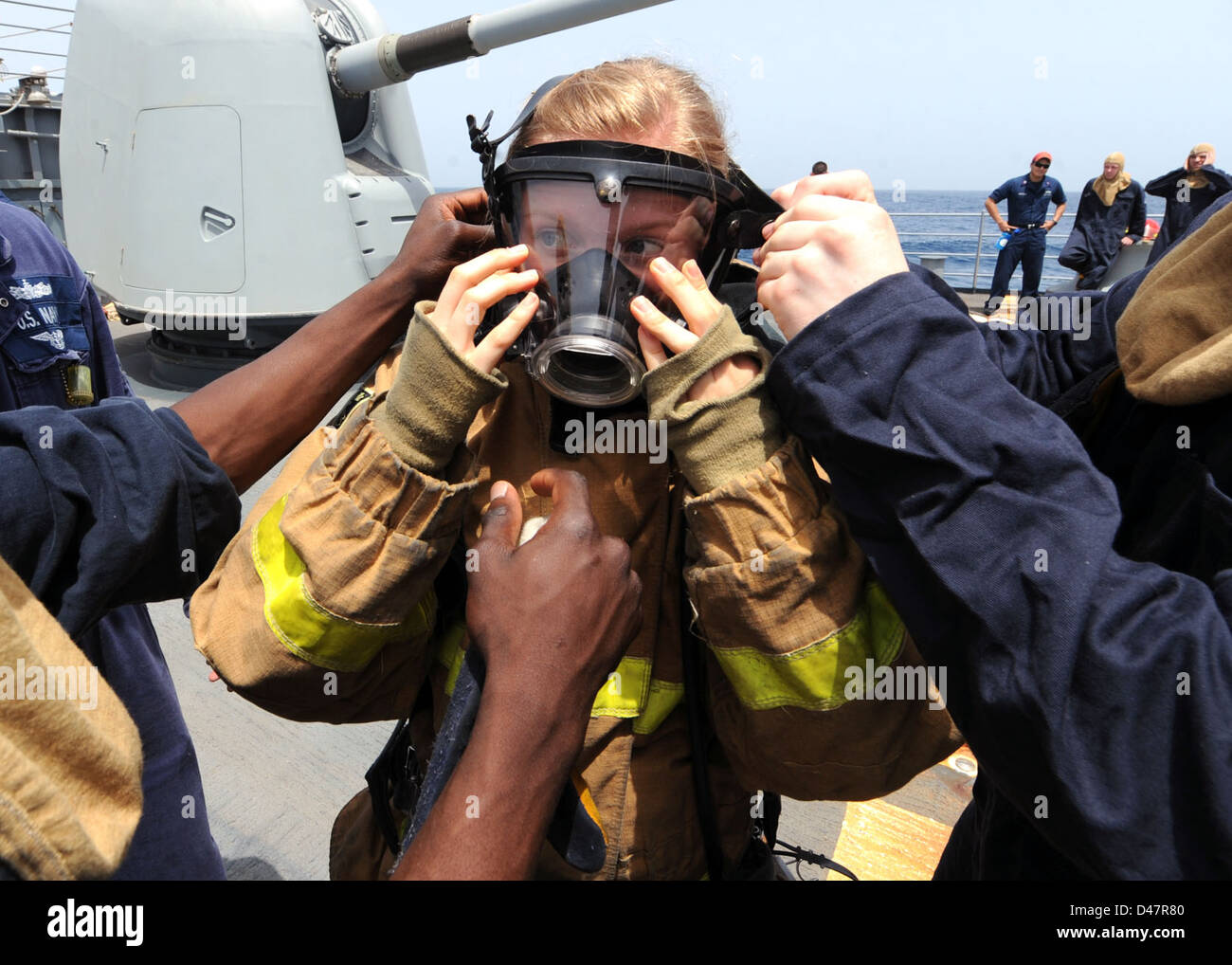 A Sailor dons firefighting equipment during a damage control drill ...