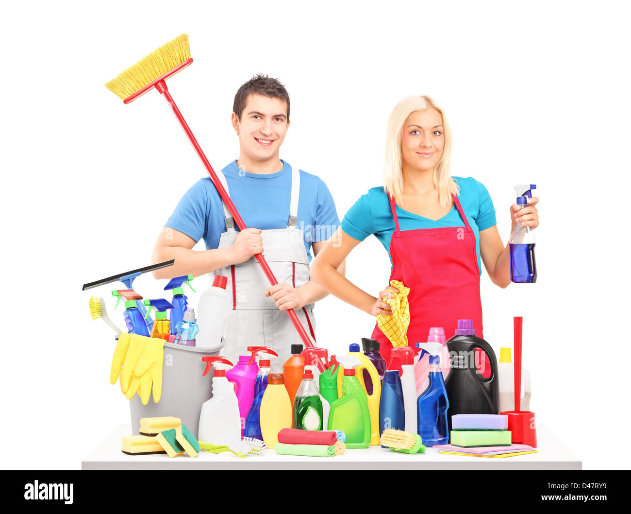 Male and female cleaners posing with cleaning supplies on a table ...