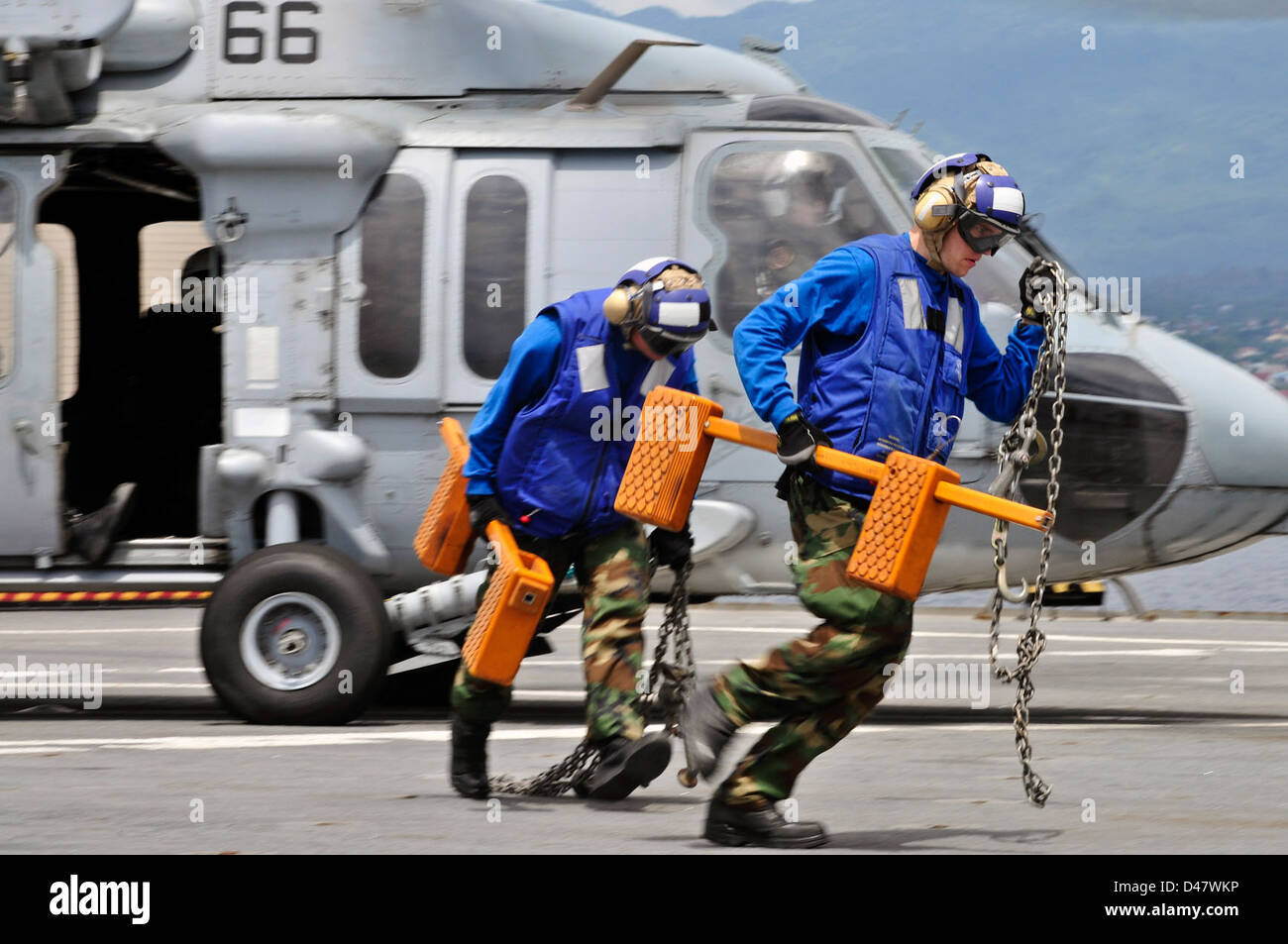 Sailors aboard a U.S. Navy ship remove the chocks and chains securing a ...