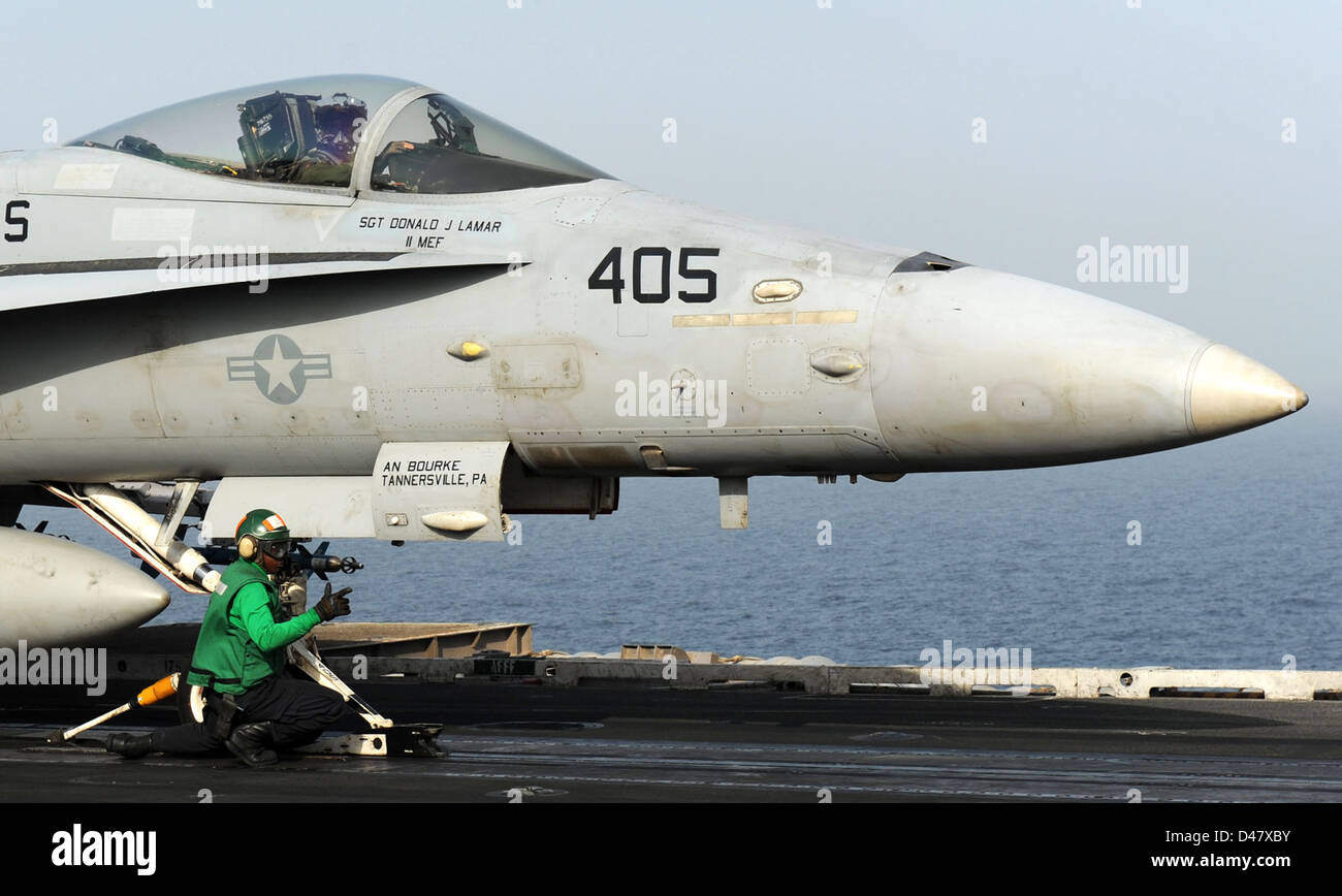 A U.S. Navy Sailor guides an aircraft into a catapult shuttle aboard an ...