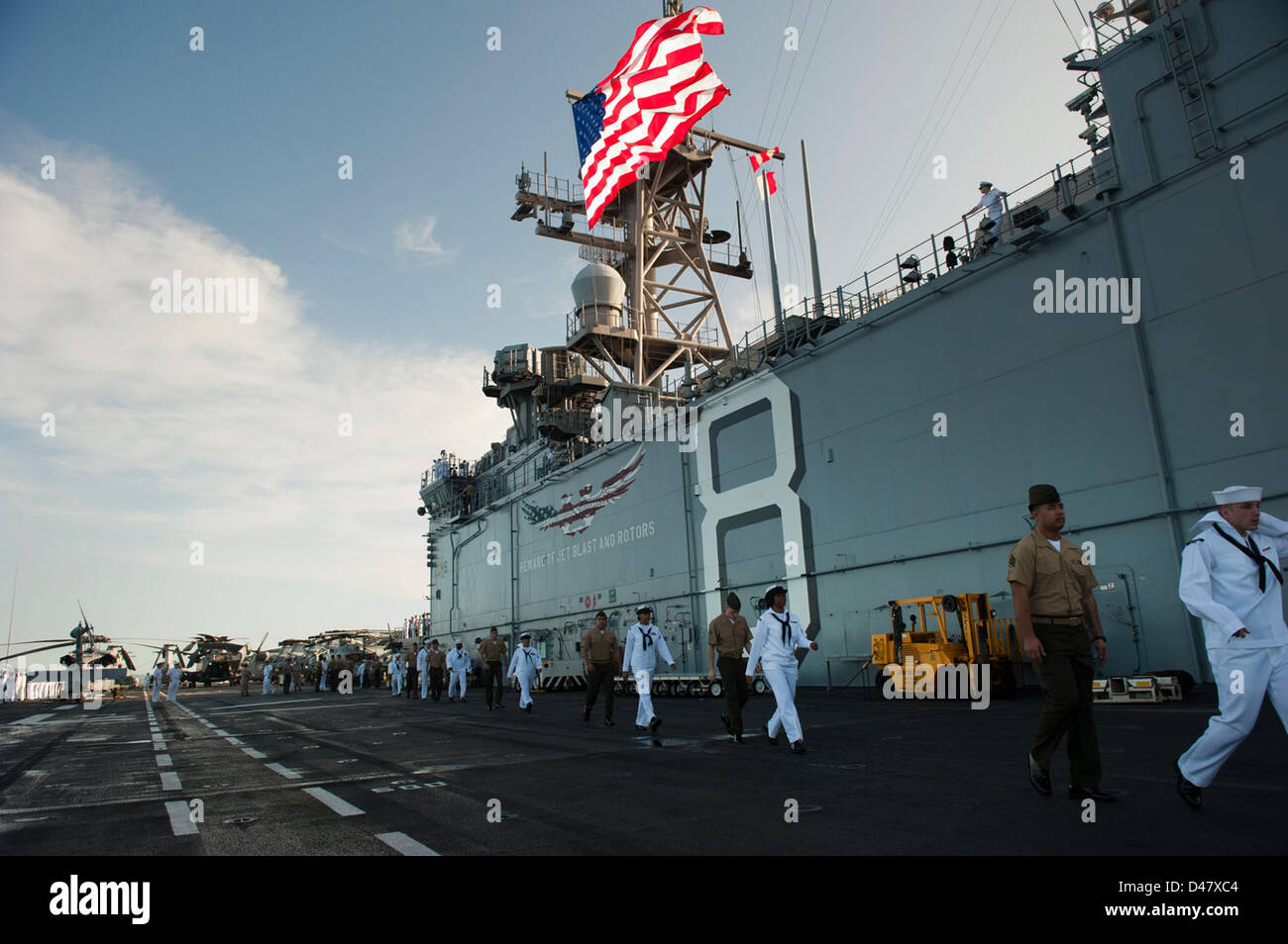 Sailors and Marines prepare to man the rails on the flight deck of USS ...