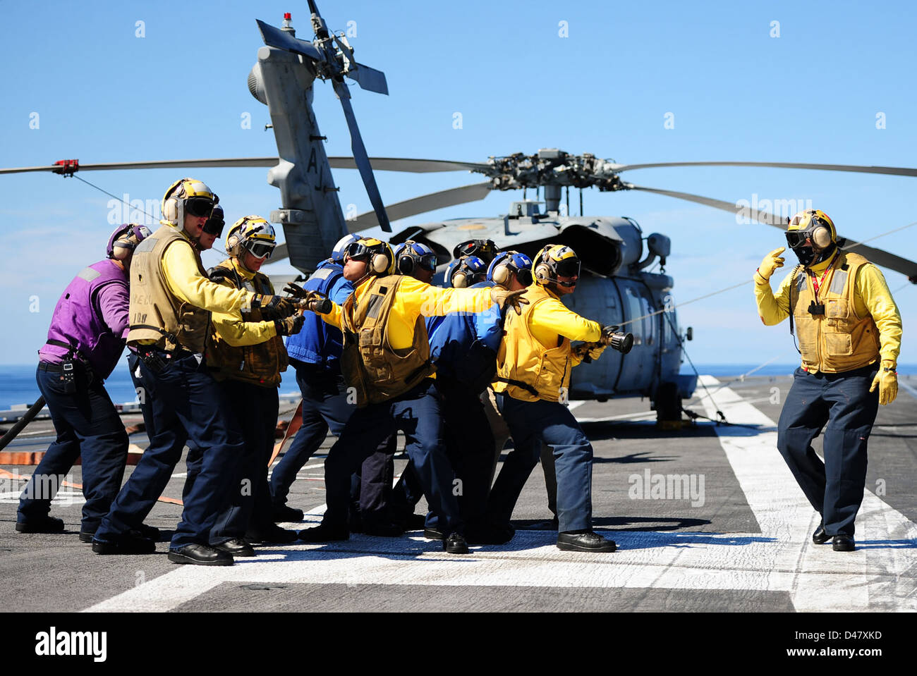 Sailors operate a fire hose aboard a U.S. Navy vessel during a fire ...