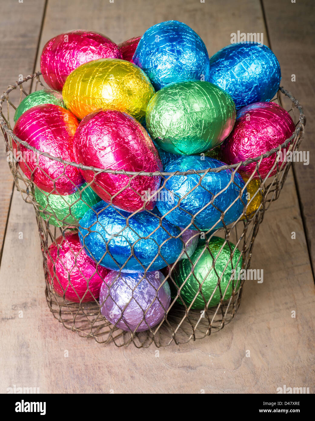 A wire egg basket with colorful foil eggs Stock Photo - Alamy