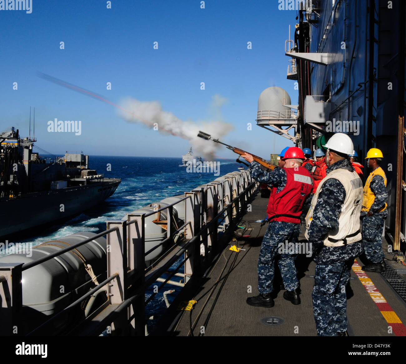 A Sailor fires a shot line from the USNS Rainier (T-AOE7) in the ...