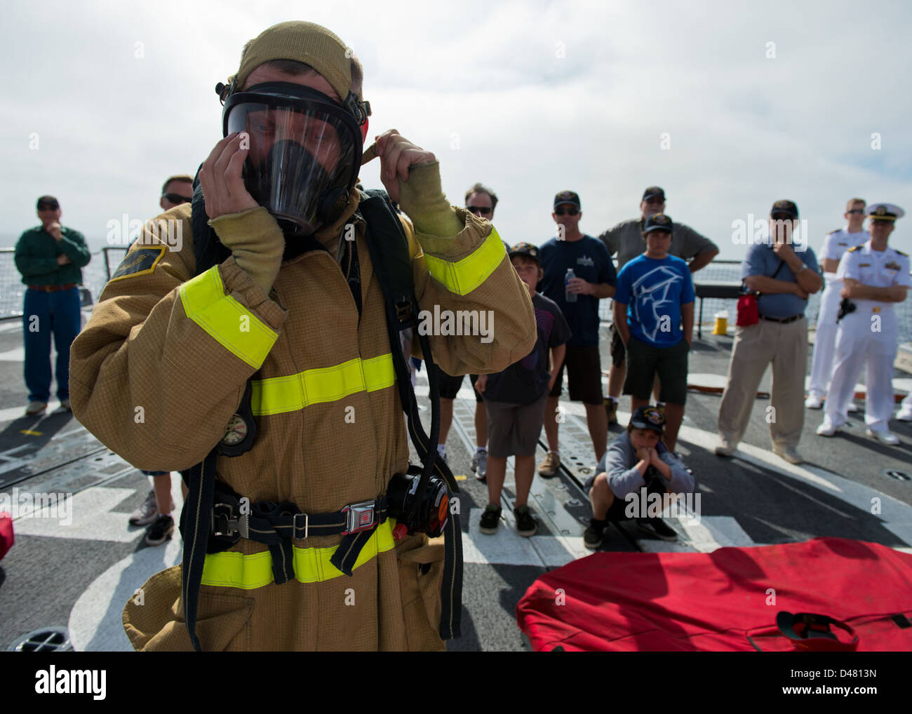 A U.S. Navy Sailor demonstrates proper technique for donning ...