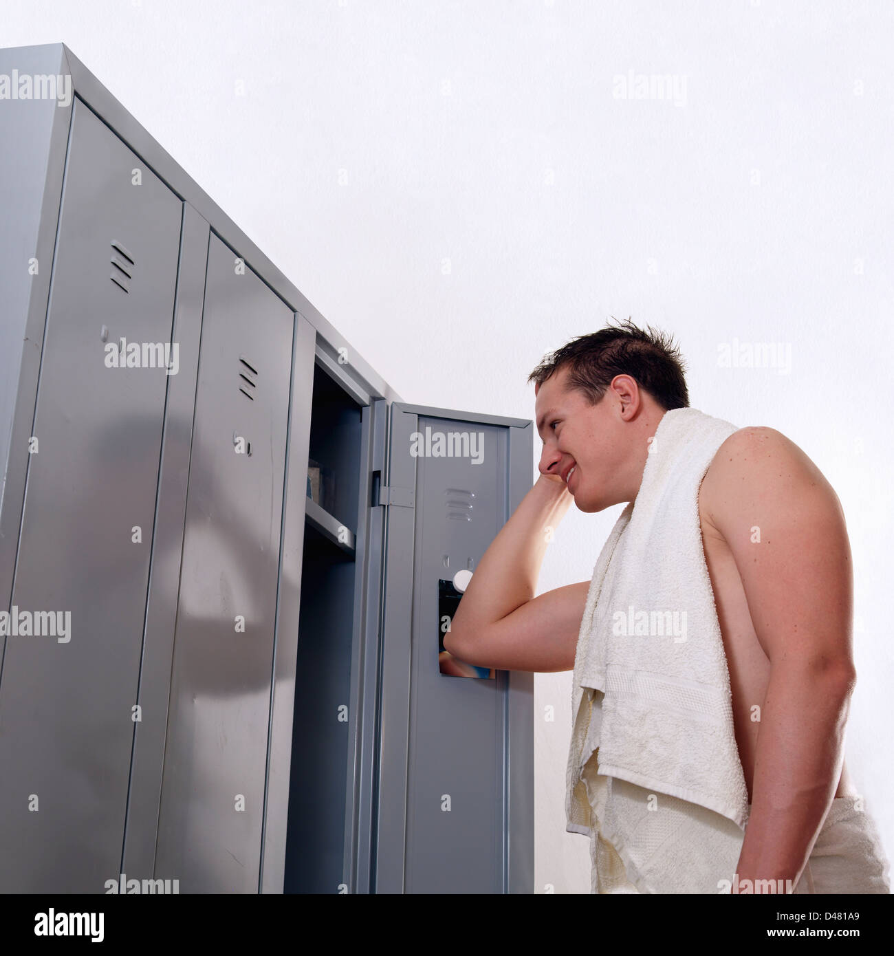 A man grooming himself in front of a gym/spa locker after a shower ...