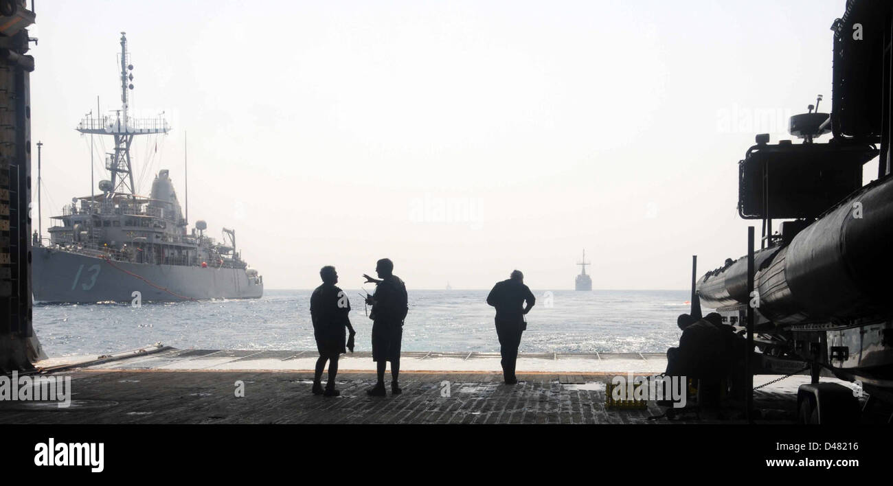 Civil service mariners aboard a U.S. Navy ship observe an astern ...