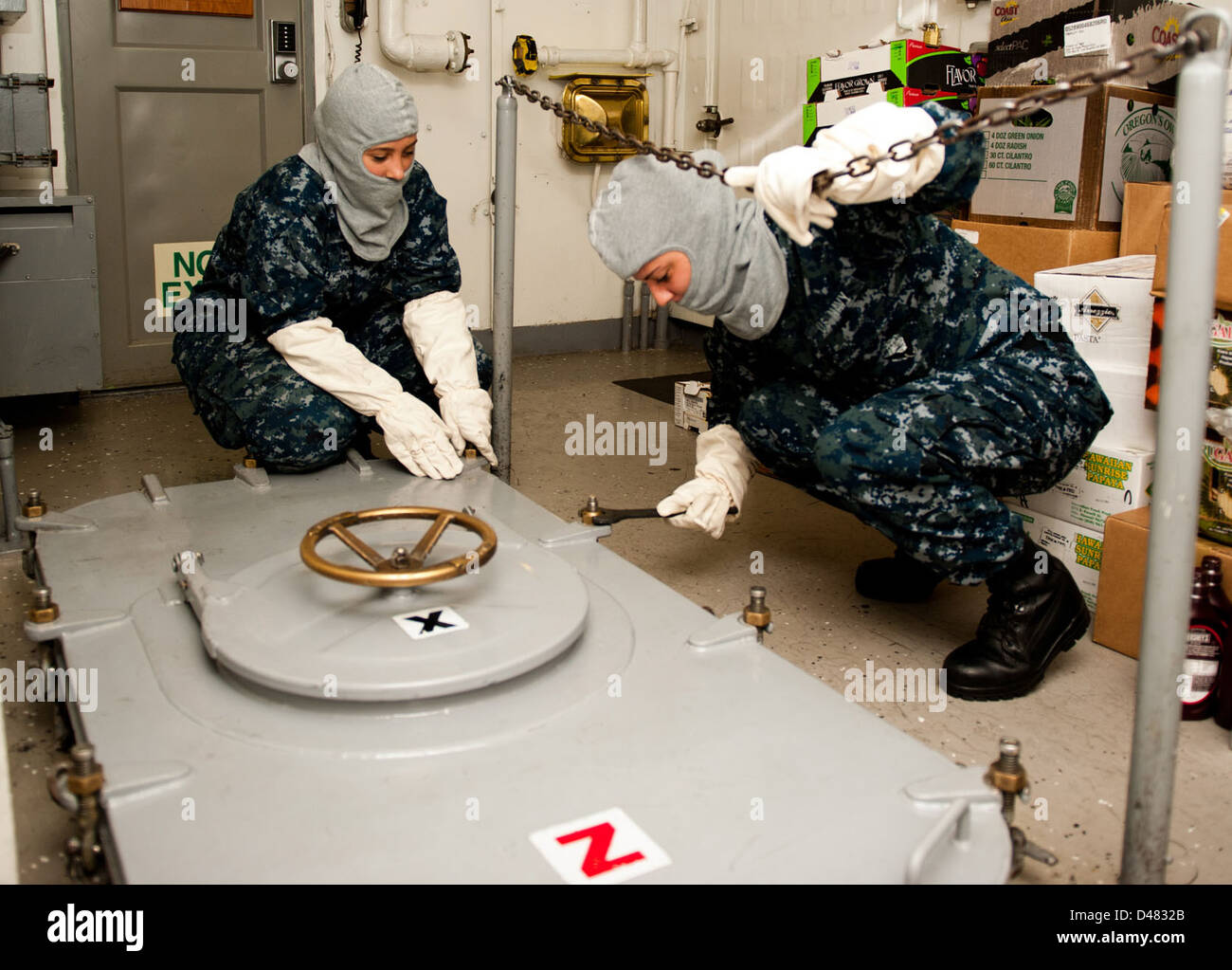 Sailors secure a water-tight hatch aboard a ship while operating in the ...