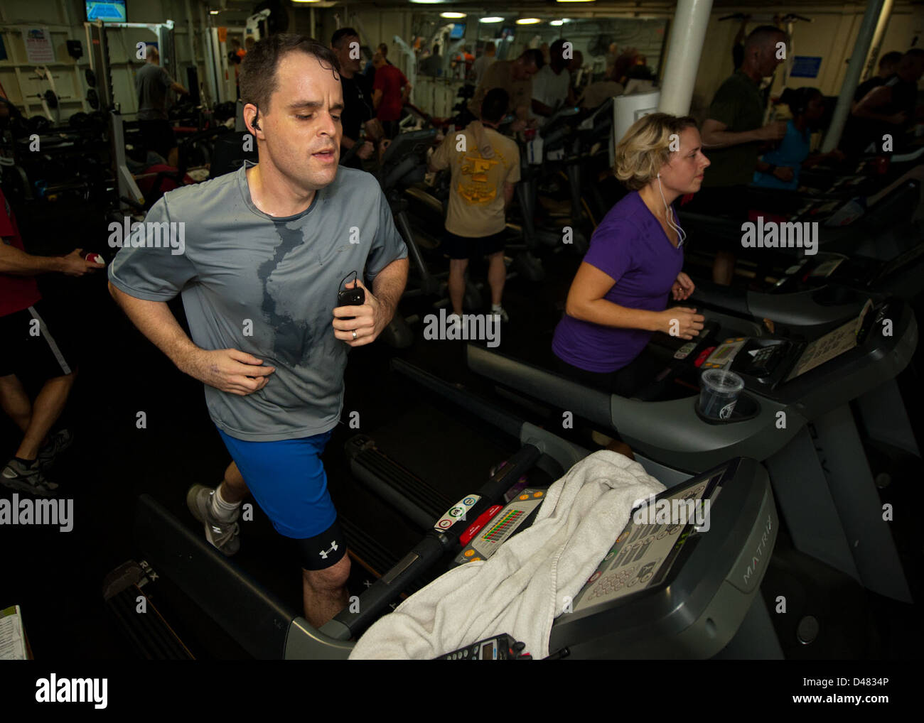 Sailors aboard a U.S. Navy carrier exercise on treadmills while ...