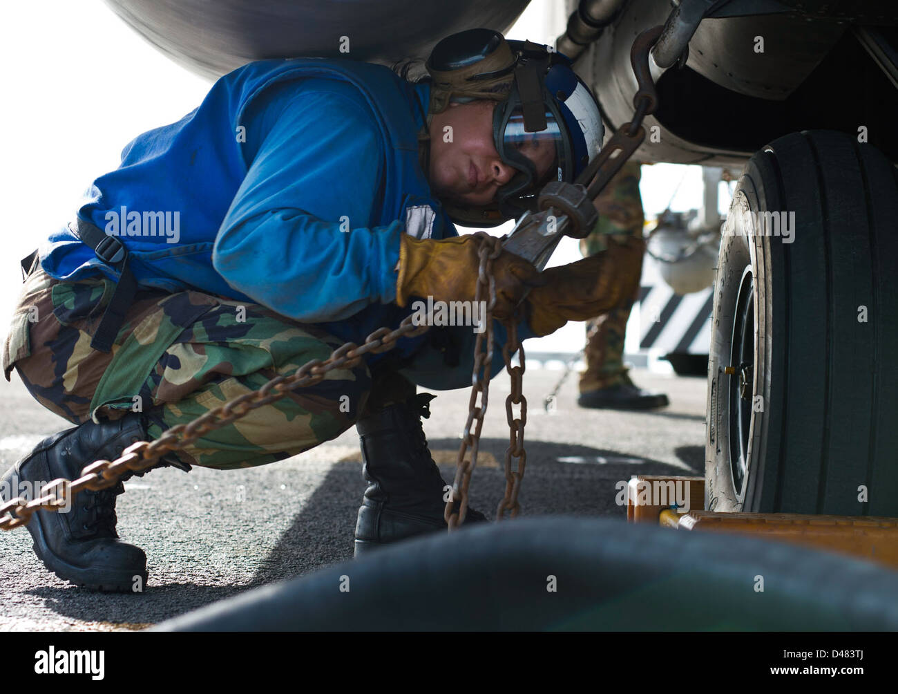 Sailor chains a helicopter on the flight deck Stock Photo - Alamy