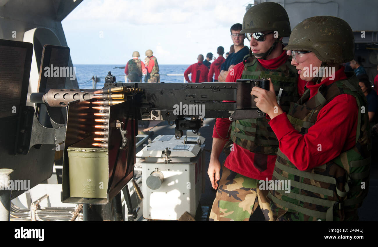 Sailors aboard a naval vessel fire a machine gun in the Pacific Ocean ...