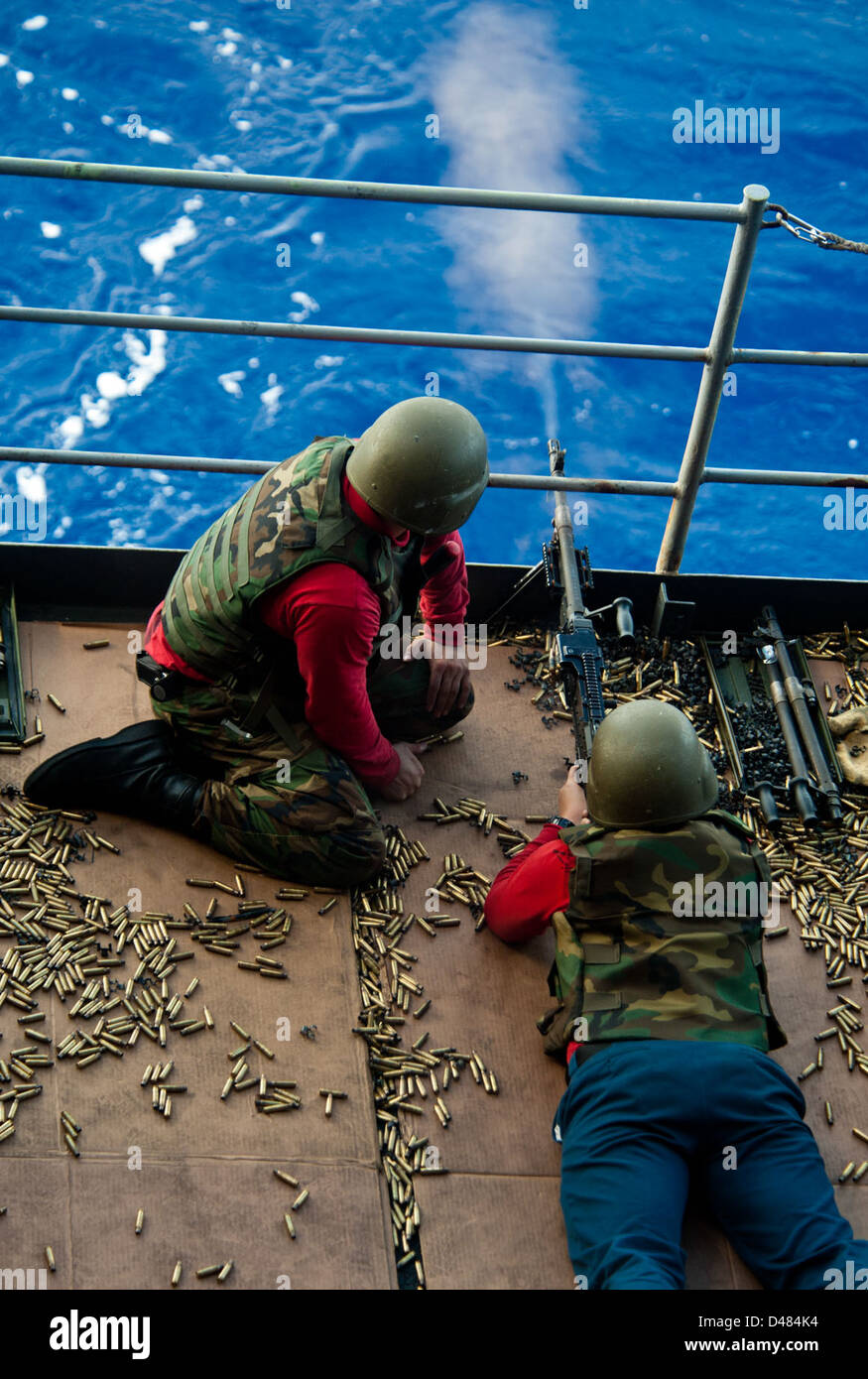 A U.S. Navy Sailor fires an M240 machine gun while aboard a ship ...