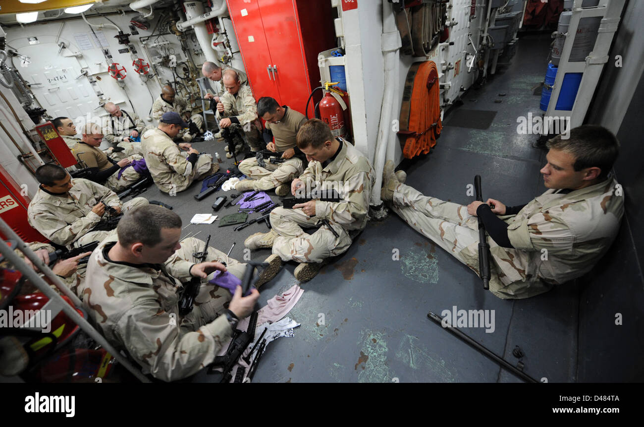 Sailors aboard a U.S. Navy vessel clean and maintain their weapons ...