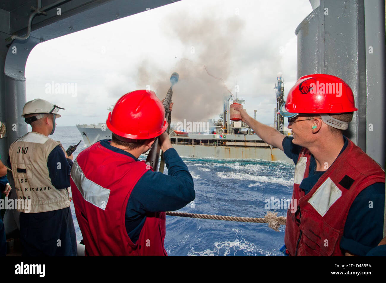 A Sailor fires a line during a replenishment at sea operation in the ...