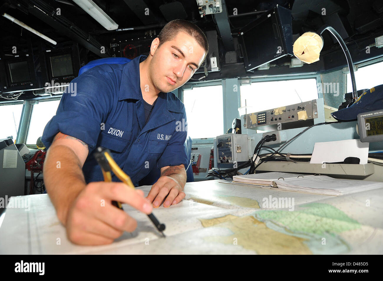 A U.S. Navy sailor plots navigation coordinates on a chart in the ...