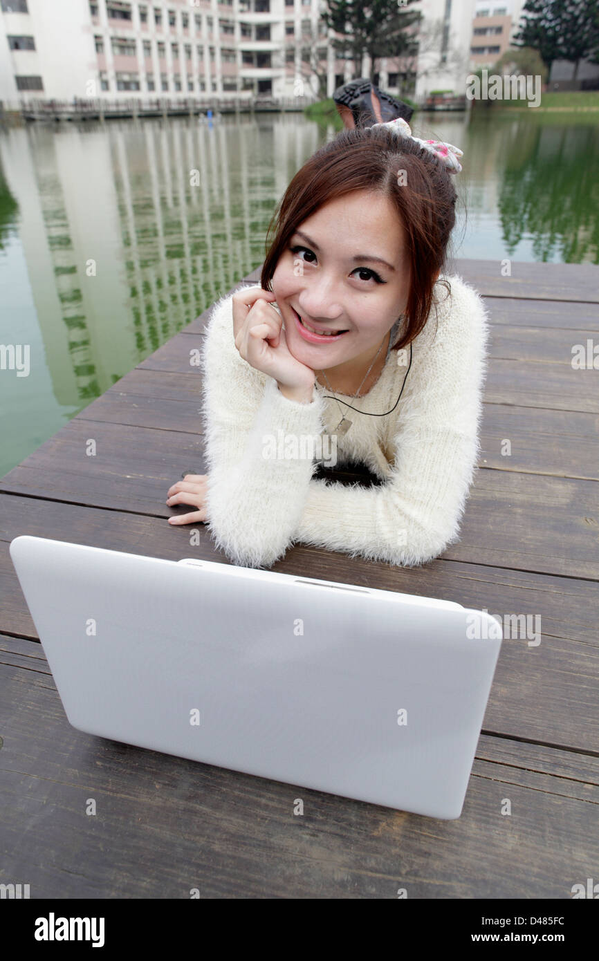 Girl student uses laptop in front of lake in university campus Stock ...