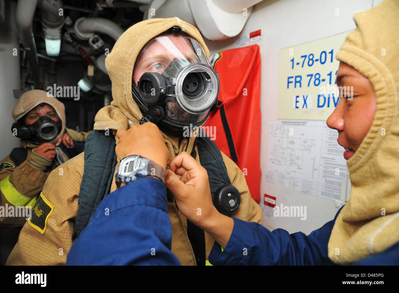 A Sailor assists with firefighting gear aboard a U.S. Navy ship in the ...