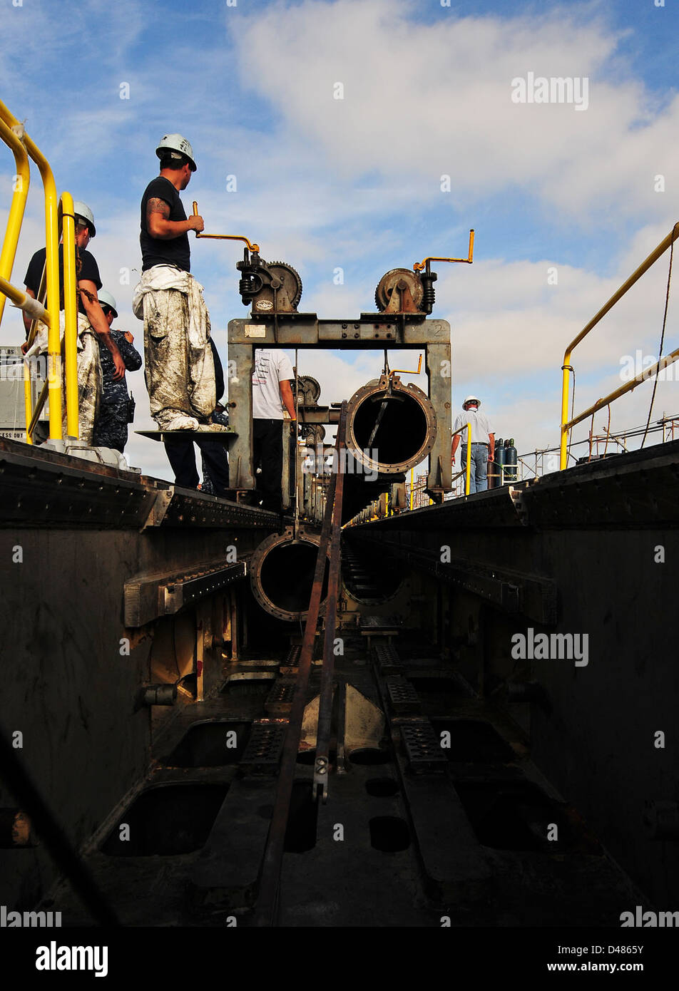 Sailors aboard a U.S. Navy vessel perform repairs on a steam catapult ...